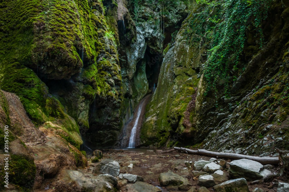 Water flow into creek and waterfall in mountain gorge, between rocks ...