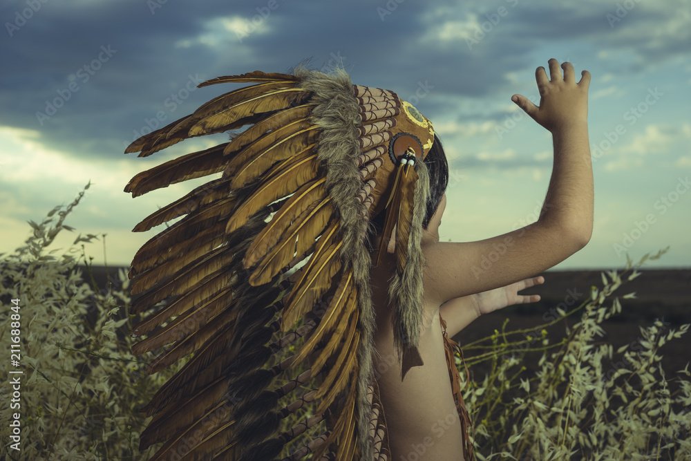 Child playing at sunset dressed as an American Indian, wearing an ...