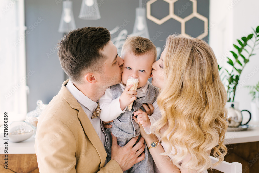 Beautiful young parents kiss their year-old child at home in a ...