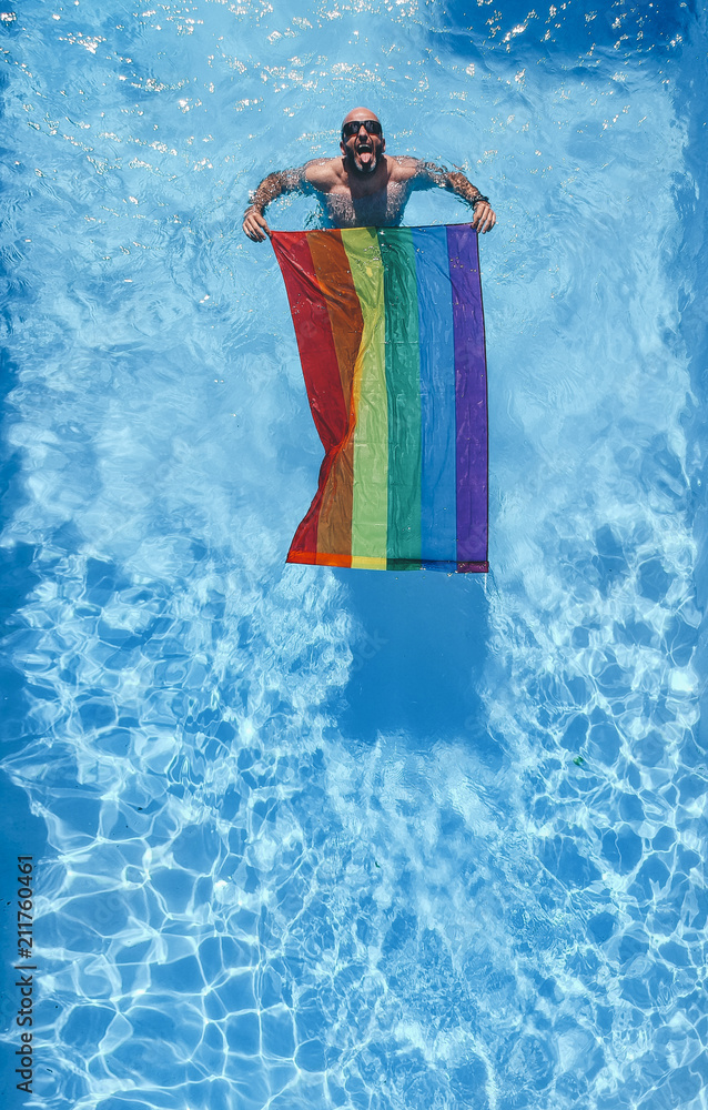 Gay man with gay pride flag in swimming pool. Stock Photo | Adobe Stock