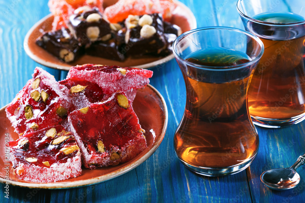 Tea in armudu glass with oriental delight rahat lokum over wooden blue ...