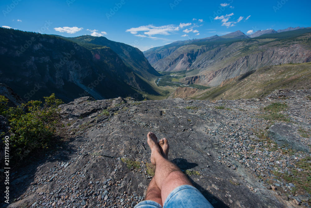 Men's feet without shoes rest on the edge of a huge and very beautiful ...