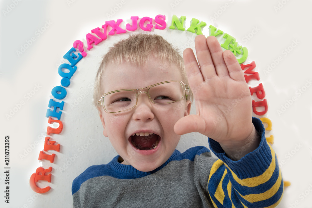 Happy charming Caucasian blond kid in colored clothes playing with ...