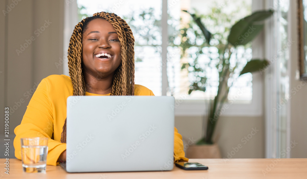 African american woman with laptop with a happy face standing and ...