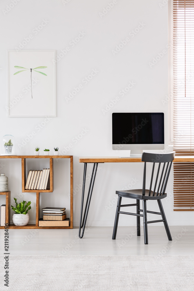 Real photo of a desk with a computer screen and a chair standing next ...