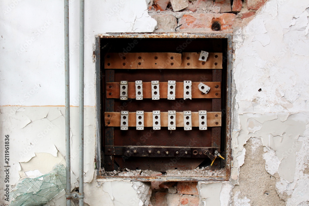 Destroyed rusted old fuse box surrounded with crumbling wall, visible ...