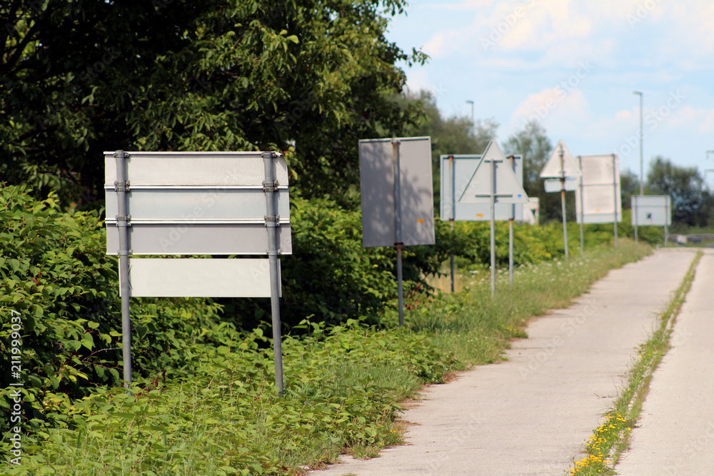 Backside of multiple road signs for different things put in a row near ...