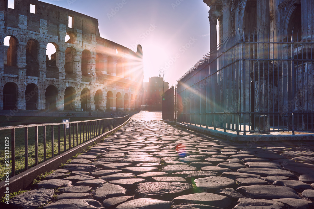 Rome, antique Roman road in cobblestones at dawn, Colosseum and Arch of ...