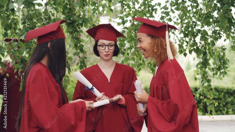 Vídeo do Stock: Three pretty girls graduates are talking and holding ...