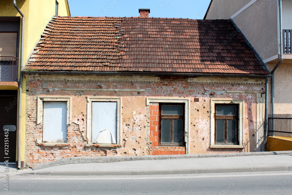 Small attached house damaged by shrapnel during war with falling facade ...
