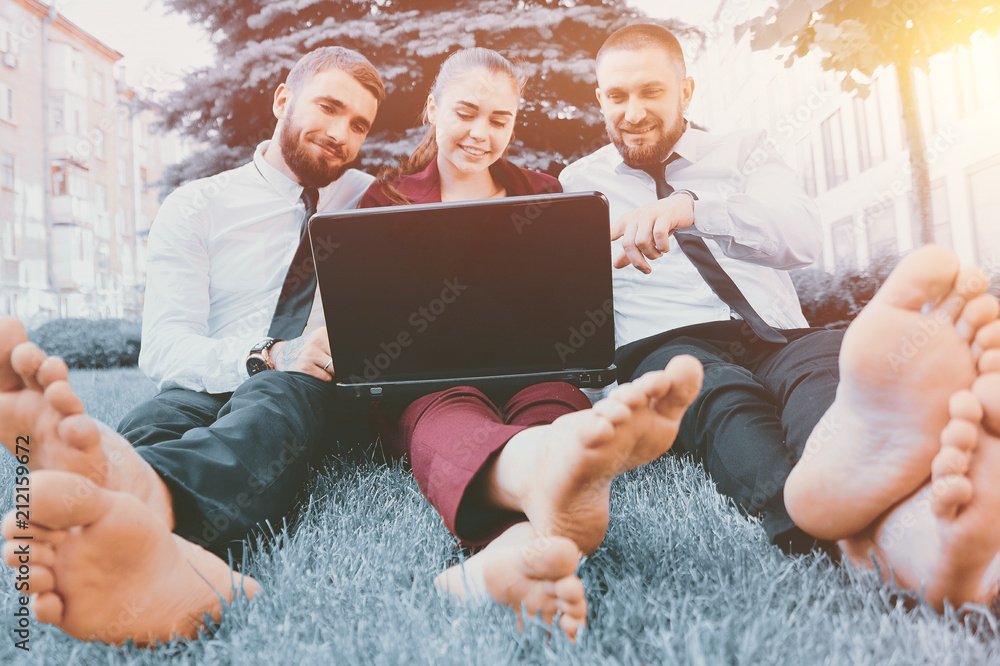 Young office workers with bare feet sit on a green lawn with a l Stock ...