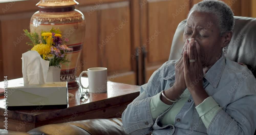 Sick elderly black woman with a cold blowing her nose with a tissue ...