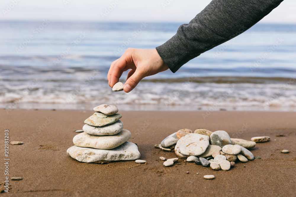 The stone in man's hand on the top of pyramid of stones for meditation ...