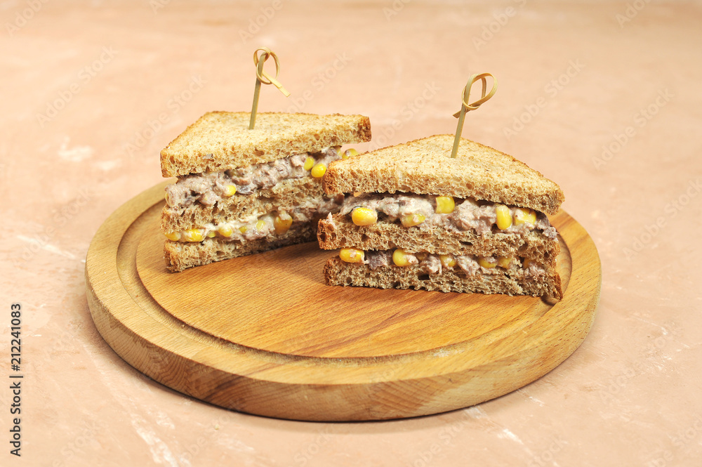 Two sandwiches of triangular shape on a wooden tray. Sandwiches are ...