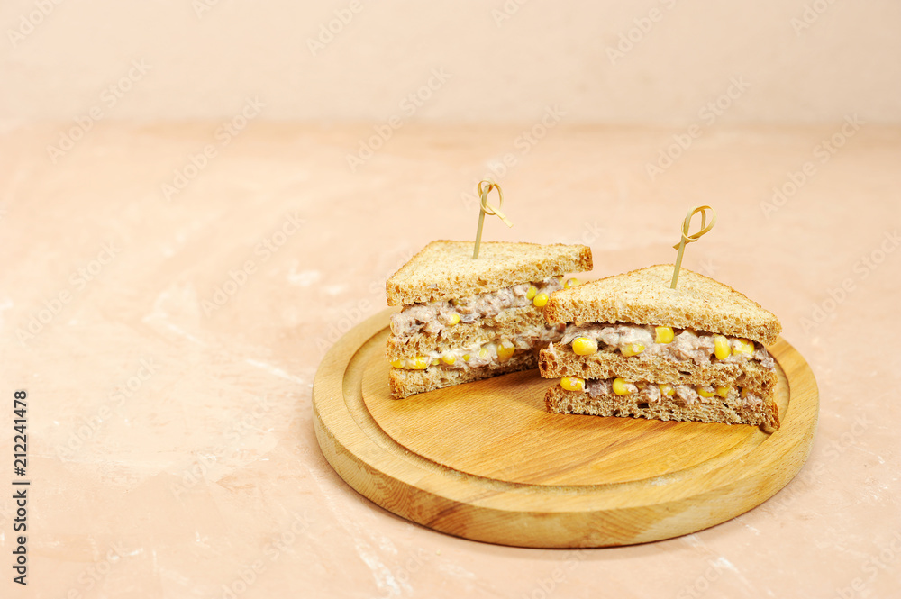 Two sandwiches of triangular shape on a wooden tray. Sandwiches are ...