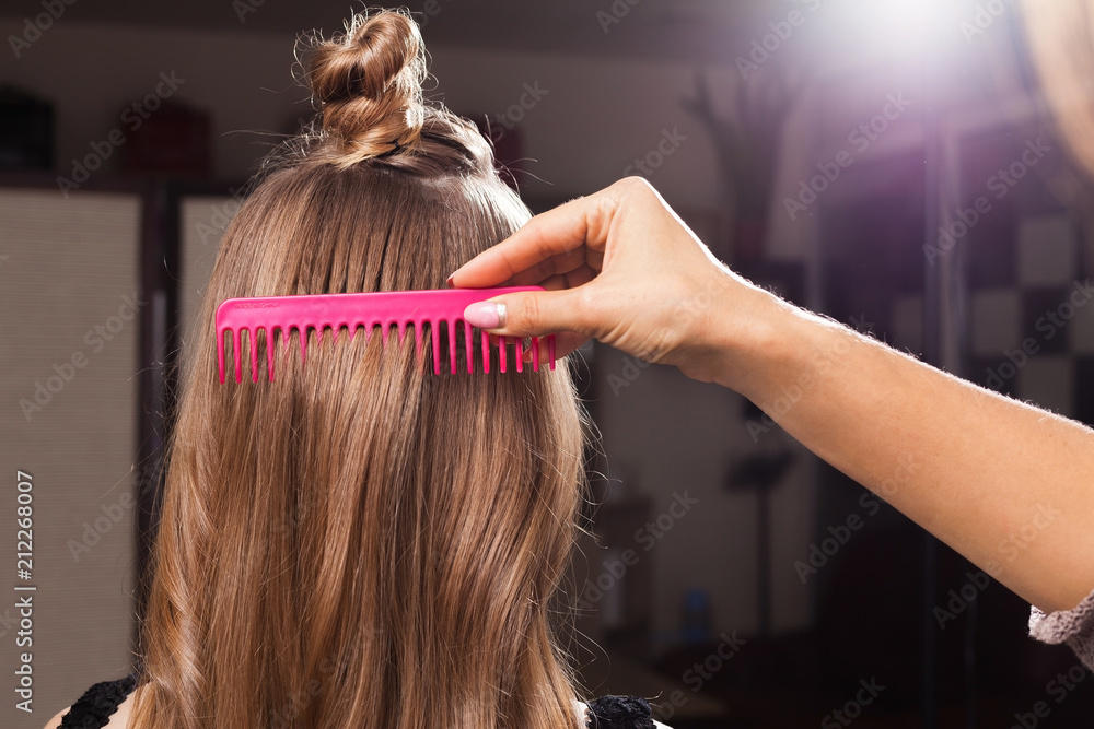 professional hairdresser brushing hair of a young model using a pink ...