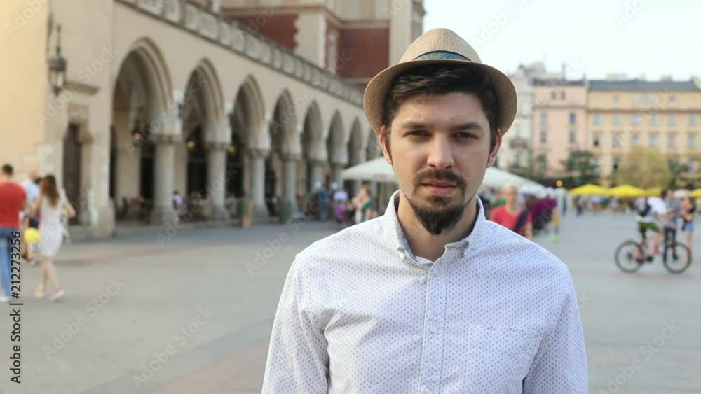 portrait of young smiling traveling man standing on city square street ...