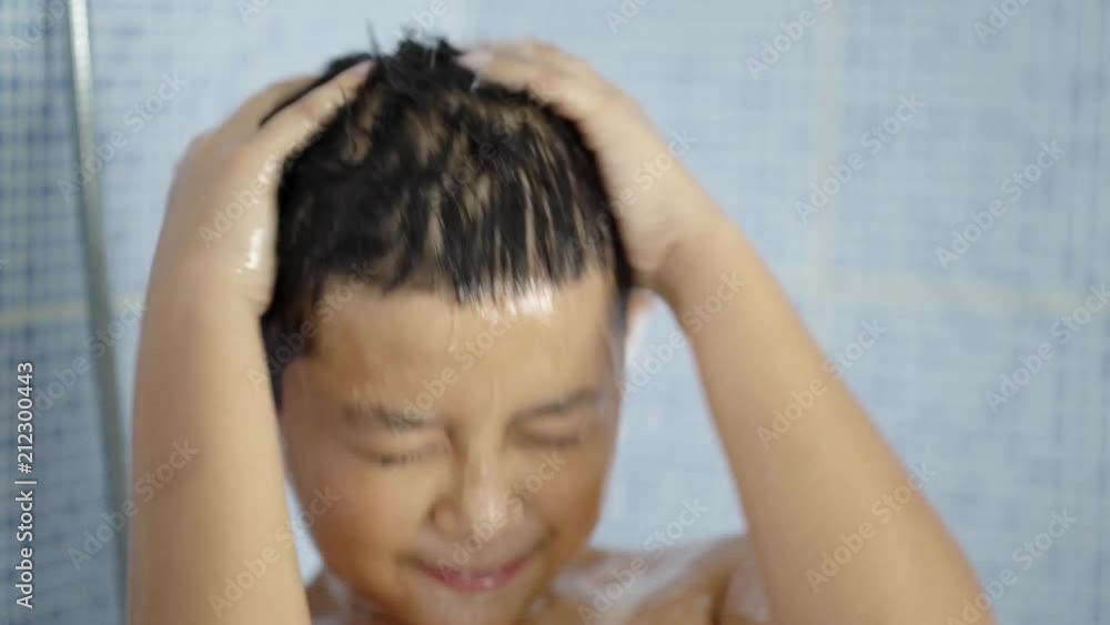 Preteen boy taking a shower while washing his hair with shampoo in the ...