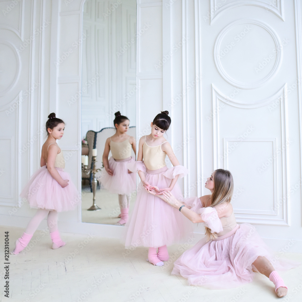 Teacher trains ballet moves with little girls in pink clothes in the ...