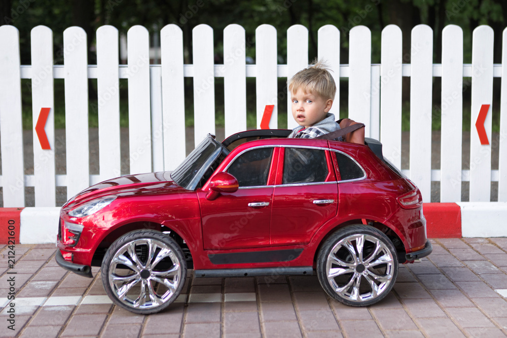 Little kid on a children's electric car is driving on special road for ...