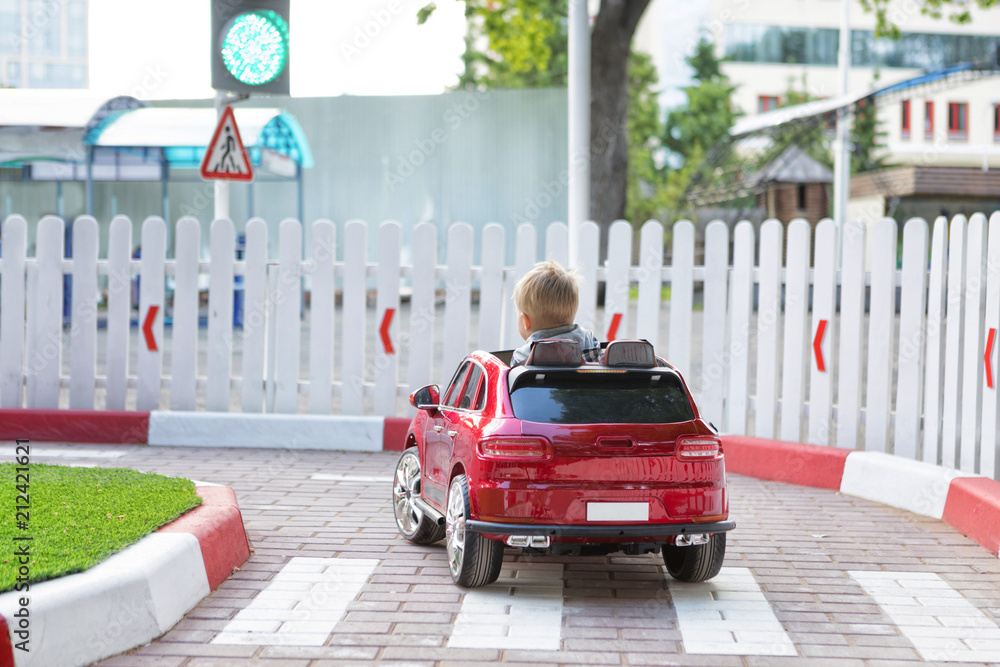 Little kid on a children's electric car is driving on special road for ...