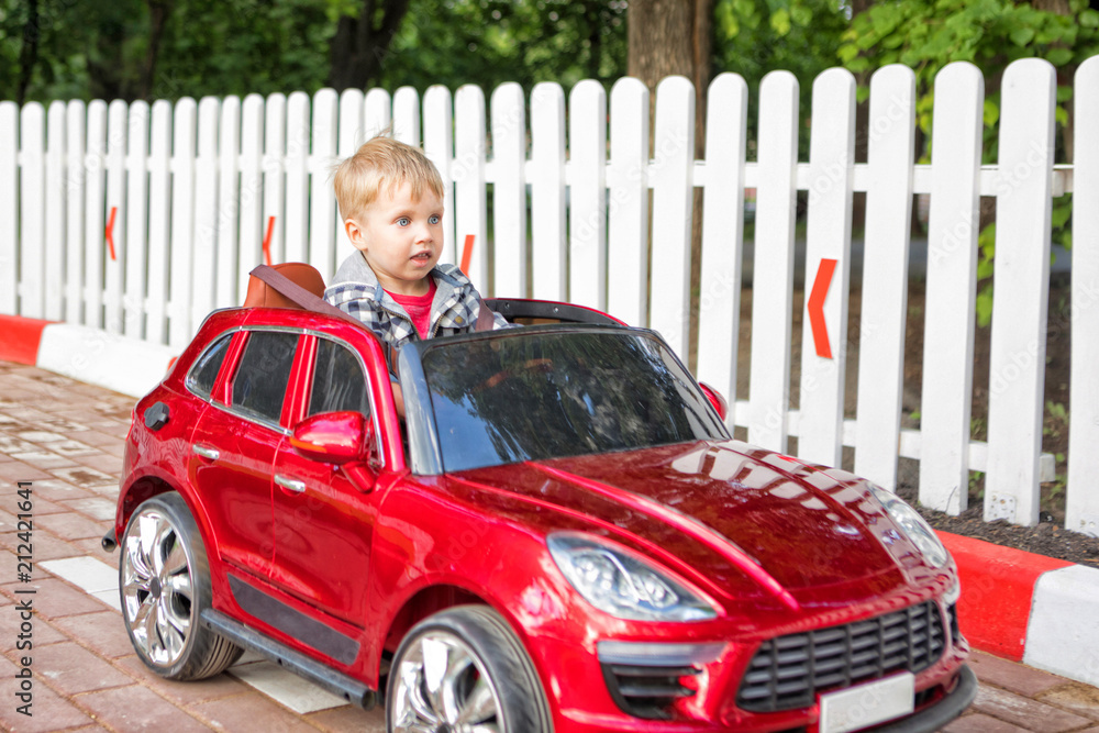Little kid on a children's electric car is driving on special road for ...