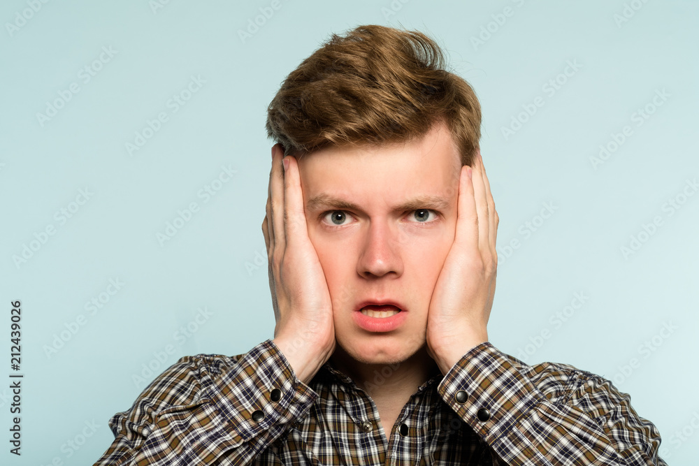shocked puzzled and bewildered man holding head in hands. portrait of a ...