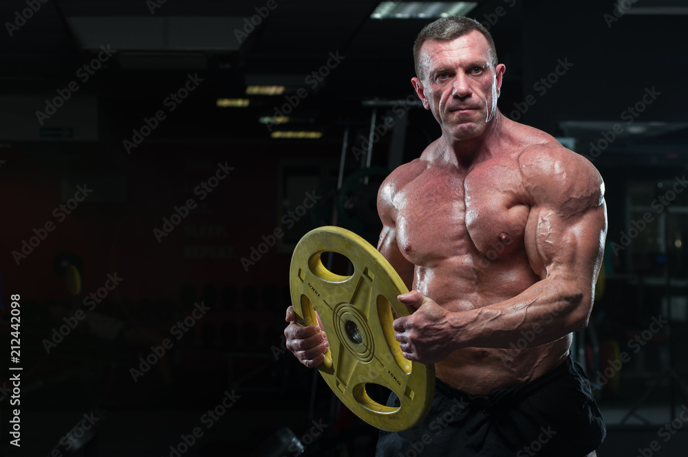 Middle aged bodybuilder posing in gym with weight in hands. Male ...