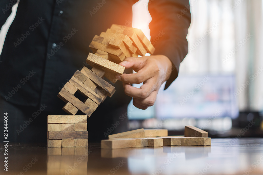 Hand of businessman pulling wood block fail on building tower at home ...