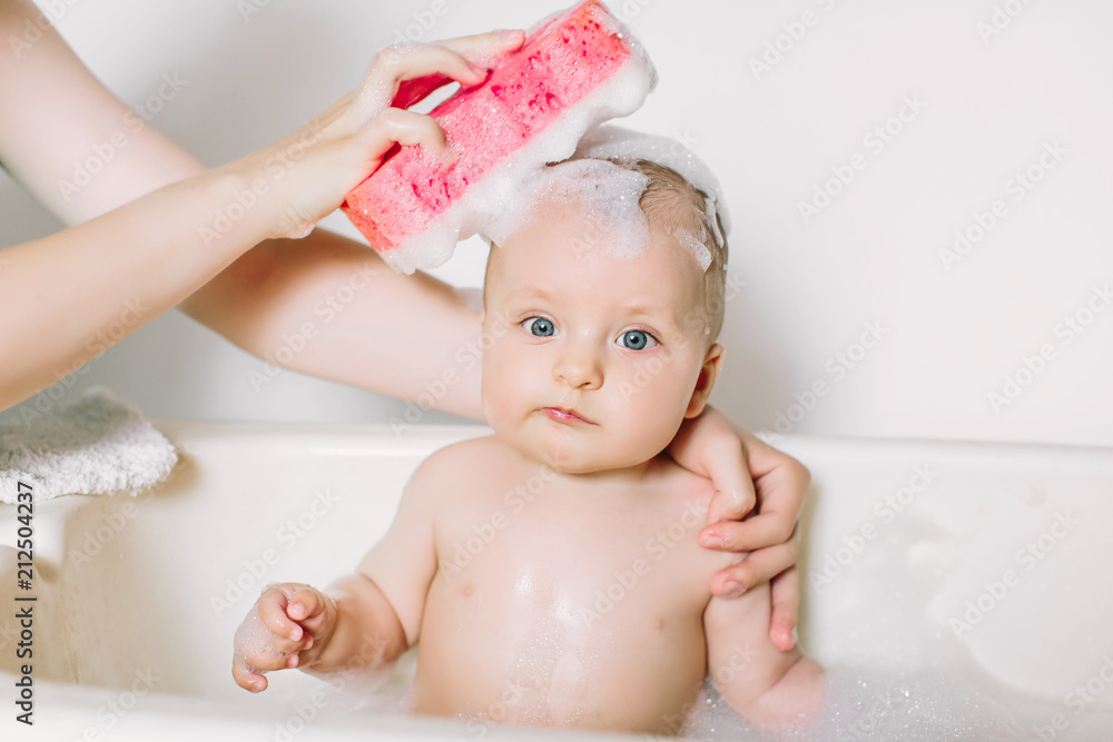 Happy laughing baby taking a bath playing with foam bubbles. Little ...