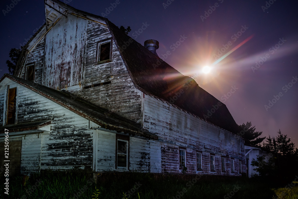 horizontal image old barn with full moon coming up behind. Night shot ...