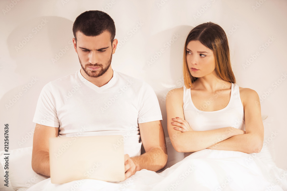 Bored Young Girl in Bed, Young Man with Laptop. Stock Photo | Adobe Stock