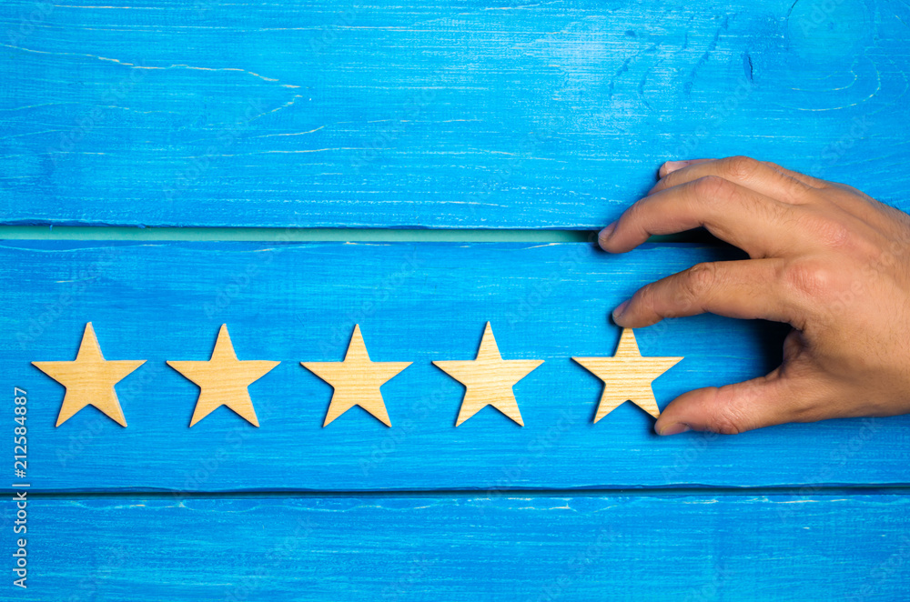 A woman's hand puts the fifth star. Quality status is five stars. A new ...