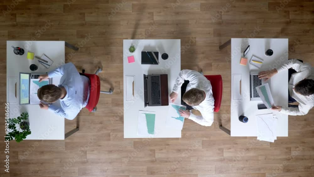 Three young businessman are working on laptops, watch diagrams ...