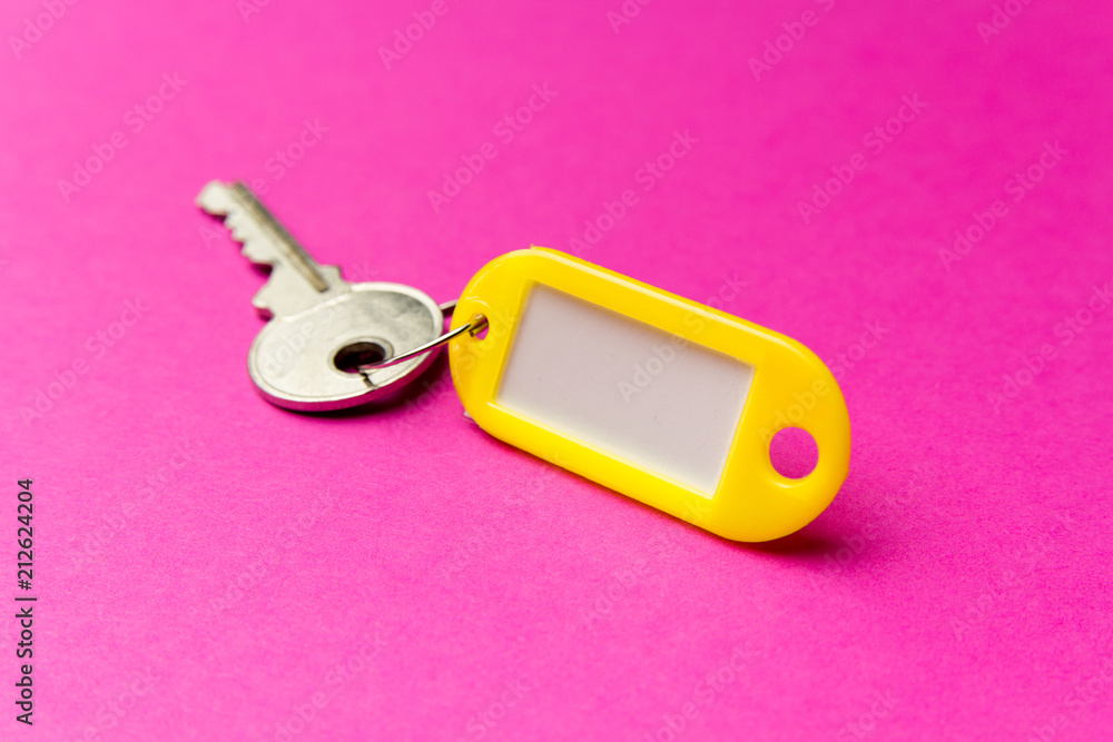 Yellow key tag on a purple textured cardboard background.The concept of ...