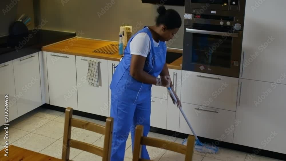 Crane shot with tilt up of black female cleaning service employee in ...