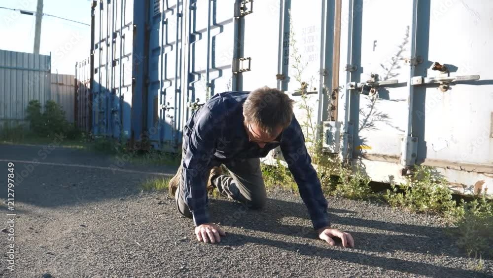 Male worker on his knees outside in the sun having a heat stroke or ...