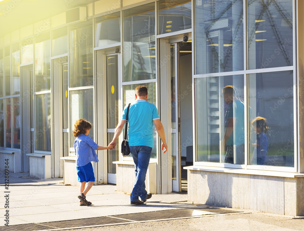Dad and son going shopping in the supermarket. They are at an entrance ...