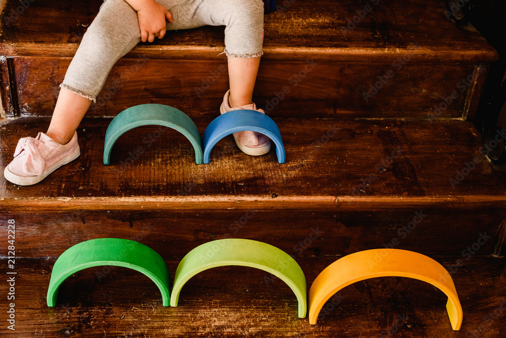 Little girl playing with waldorf montessori rainbow of various colors ...