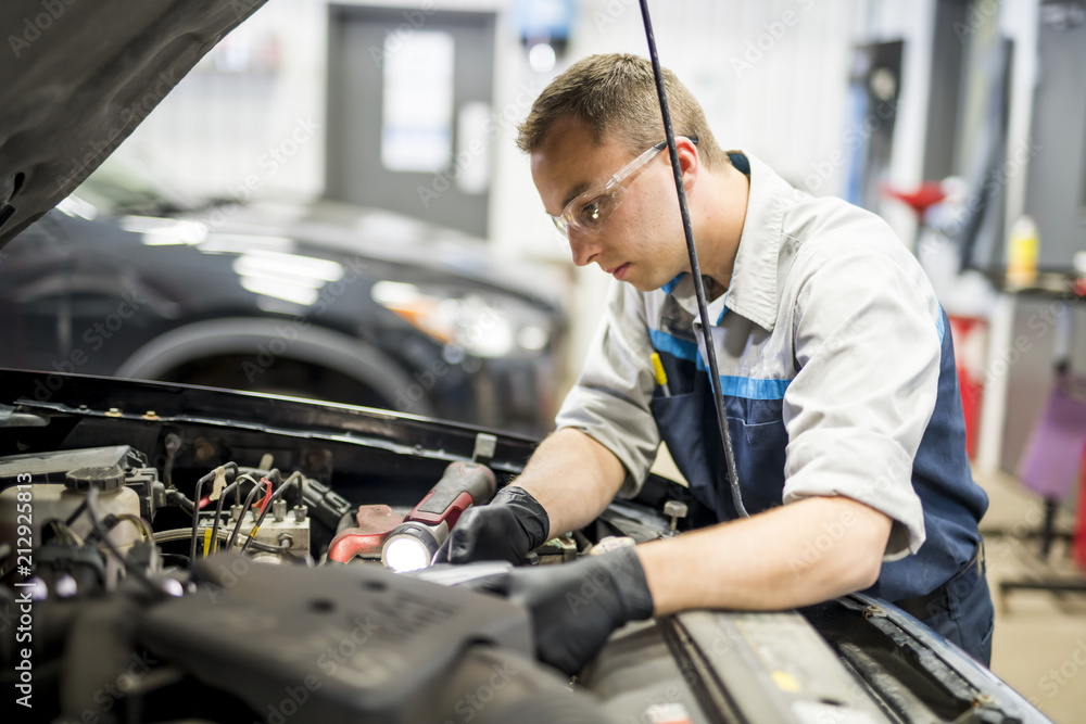 Handsome mechanic job in uniform working on car Stock Photo | Adobe Stock