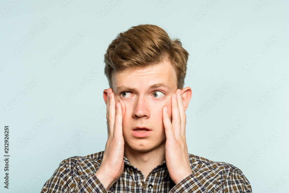 puzzled confused bewildered shocked amazed man clutching his face. portrait of a young guy on ...