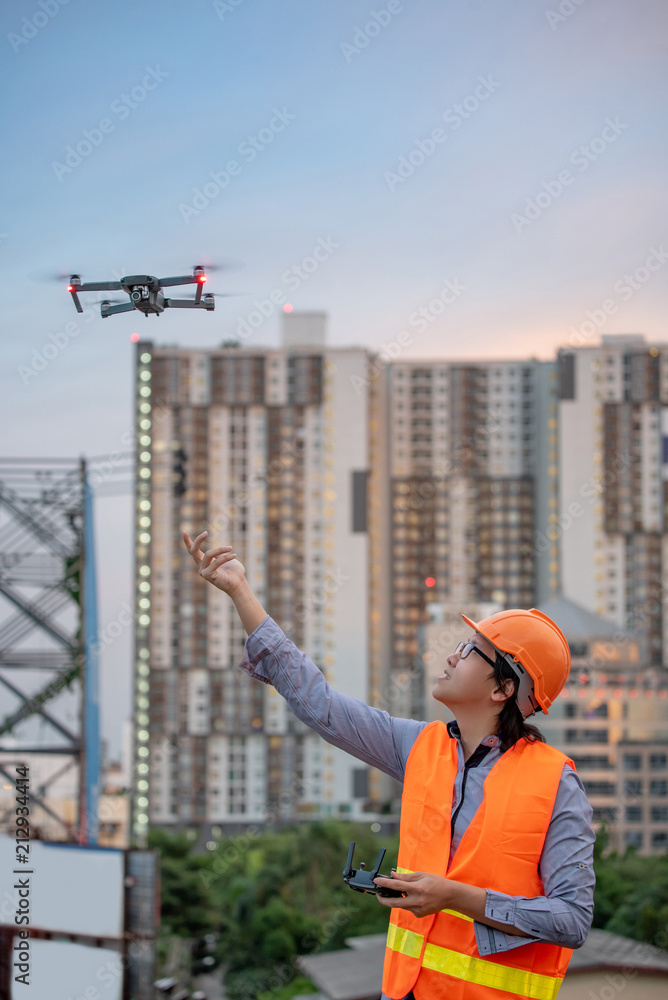 Young Asian engineer man flying drone over construction site during ...