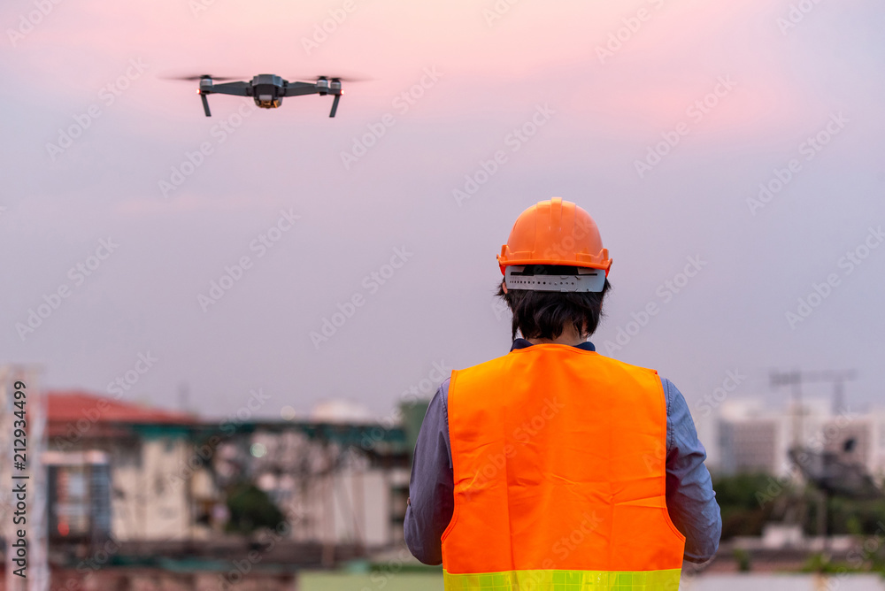 Young Asian engineer man flying drone over construction site during ...