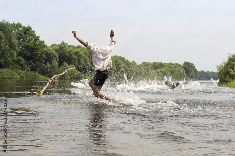 Foto de Back view of a young man that running on the river and ...