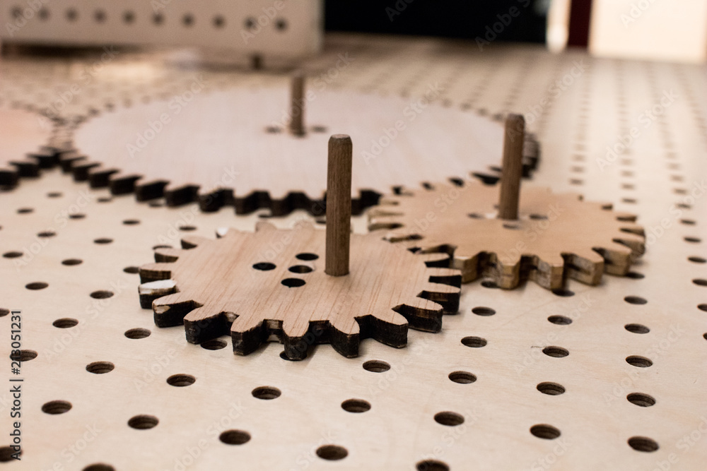 Gear wheels of wooden gears on a perforated table assembled together to ...