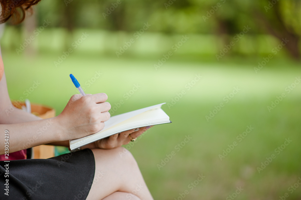 girls hands with pen writing on notebook in park . Asian girls sitting ...
