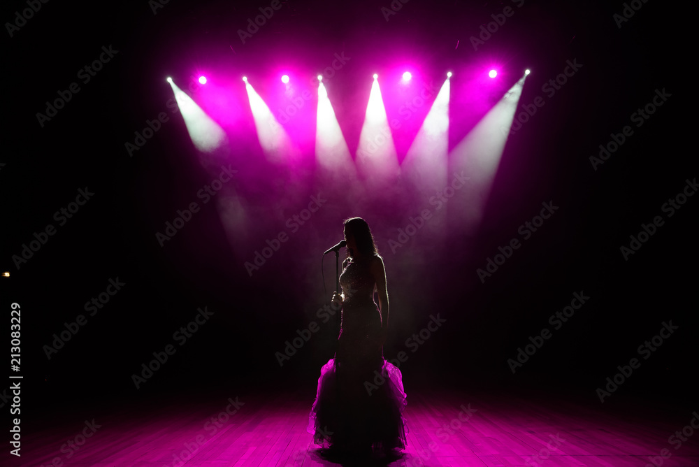 Girl in long gown performing on stage. Girl singing on the stage in ...