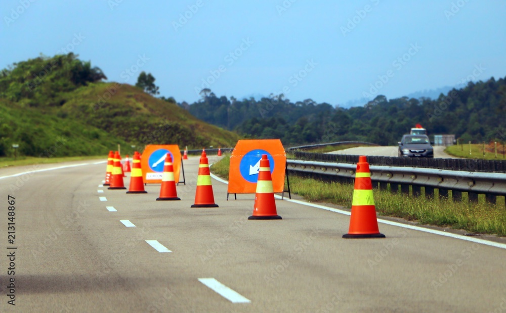 Traffic cones and a sign with a white arrow on highway as warning sign ...