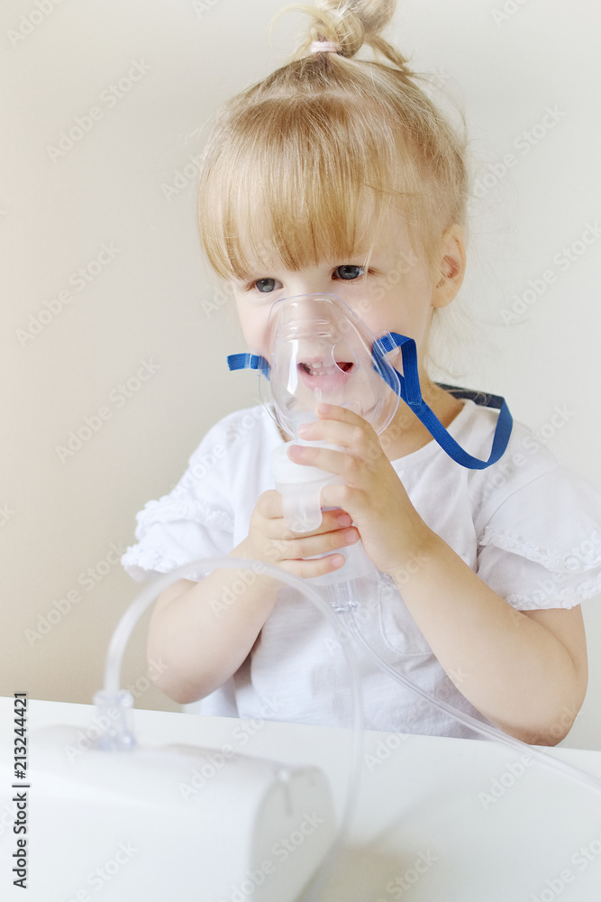Little girl in a mask for inhalations, making inhalation with nebulizer ...