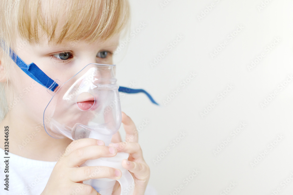 Little girl in a mask for inhalations, making inhalation with nebulizer ...